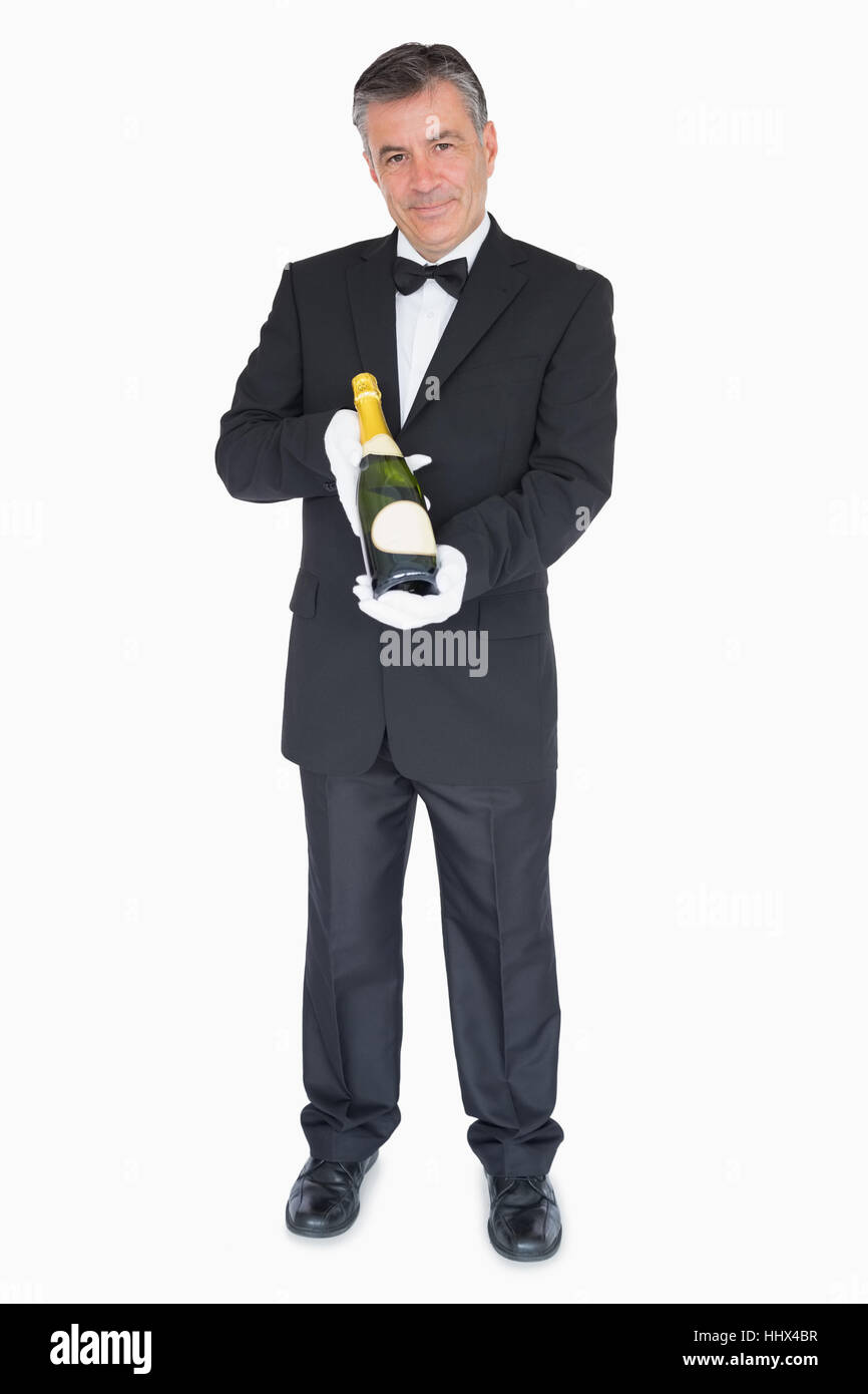 Smiling waiter offering bottle of champagne Stock Photo - Alamy