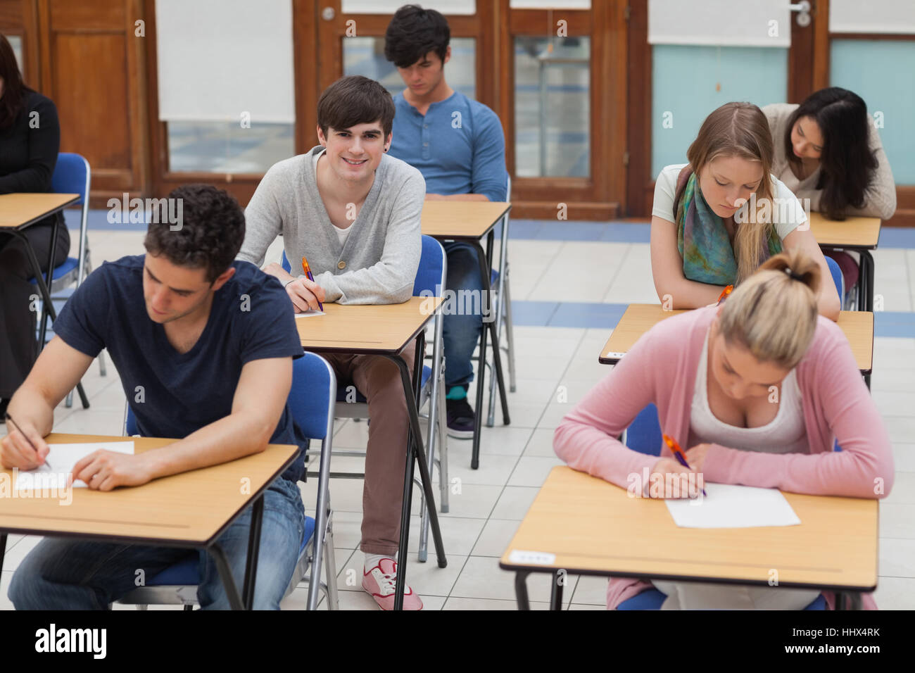 Students sitting in exam room with one boy looking up and smiling Stock ...