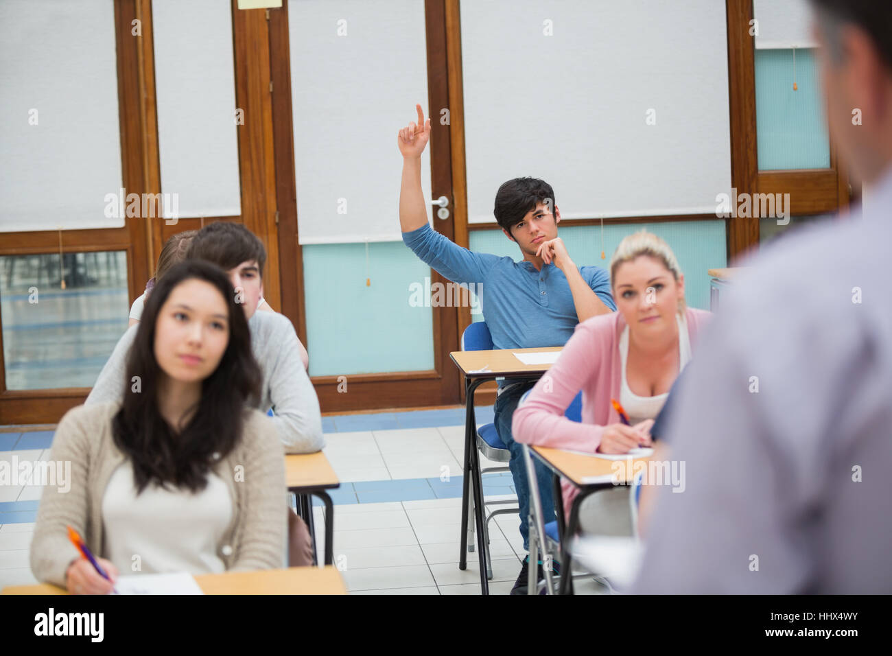 Student raising hand to ask question in college classroom Stock Photo ...