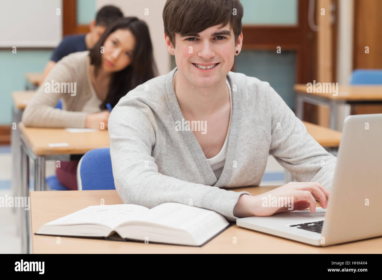 Student sitting at the classroom with laptop while smiling Stock Photo ...