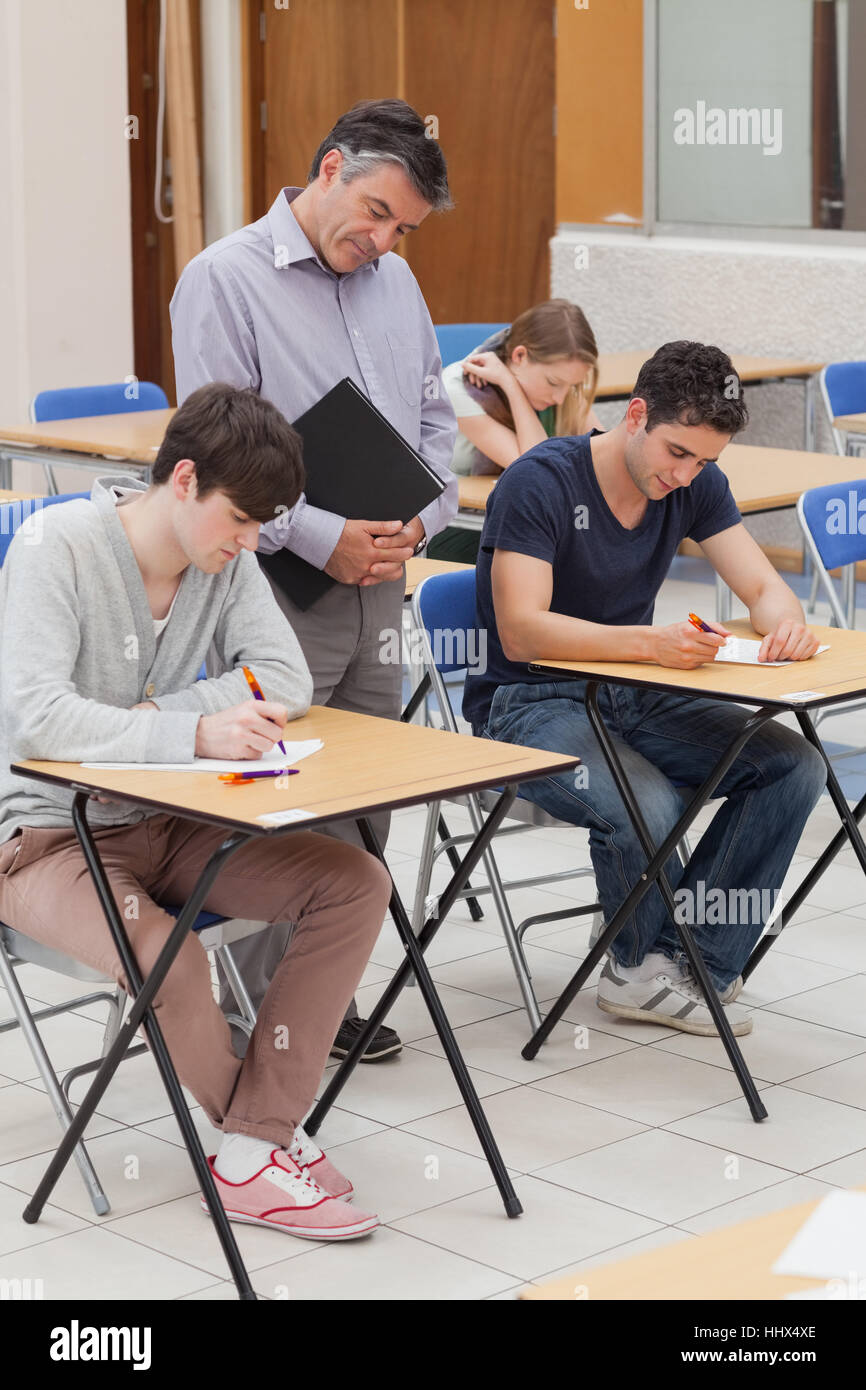 Teacher is standing next to the students at the classroom Stock Photo ...