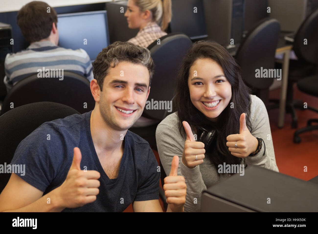 Happy students giving thumbs up in computer class Stock Photo - Alamy