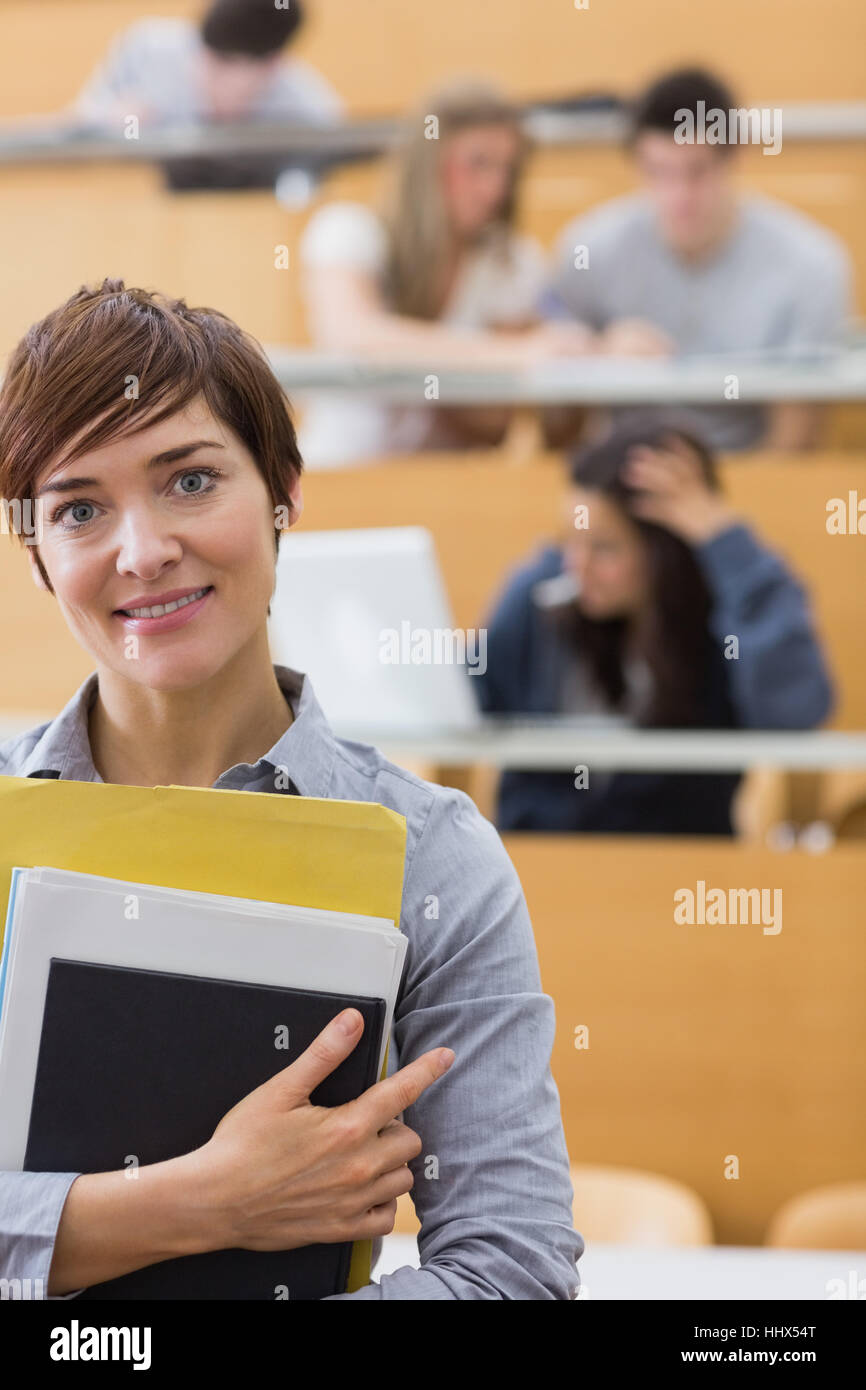 Teacher standing at the lecture hall holding folders Stock Photo - Alamy