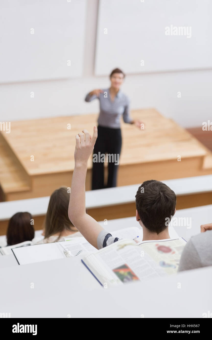 Teacher standing explaining while student hands up Stock Photo - Alamy