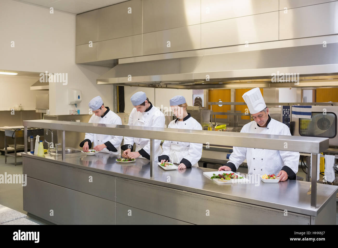 Four Chef's preparing plates in the kitchen Stock Photo - Alamy