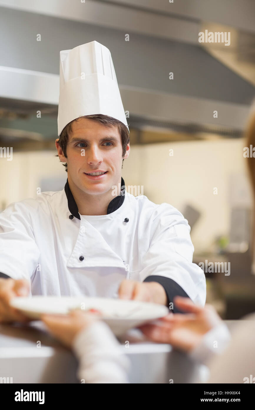 Chef passing plate to waitress at order station in kitchen Stock Photo ...
