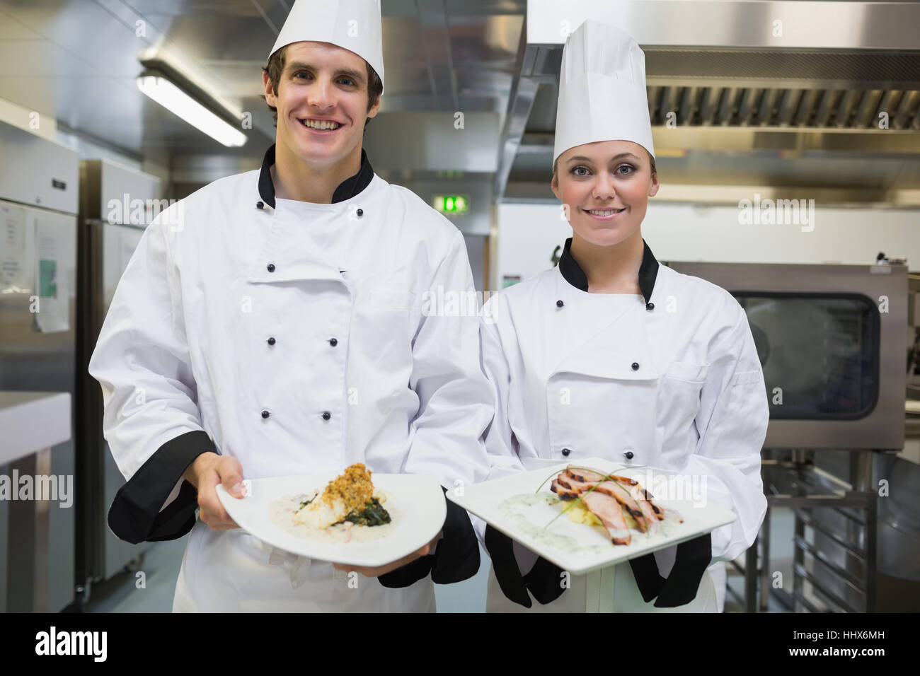 Two smiling Chef's showing plates in the kitchen Stock Photo - Alamy
