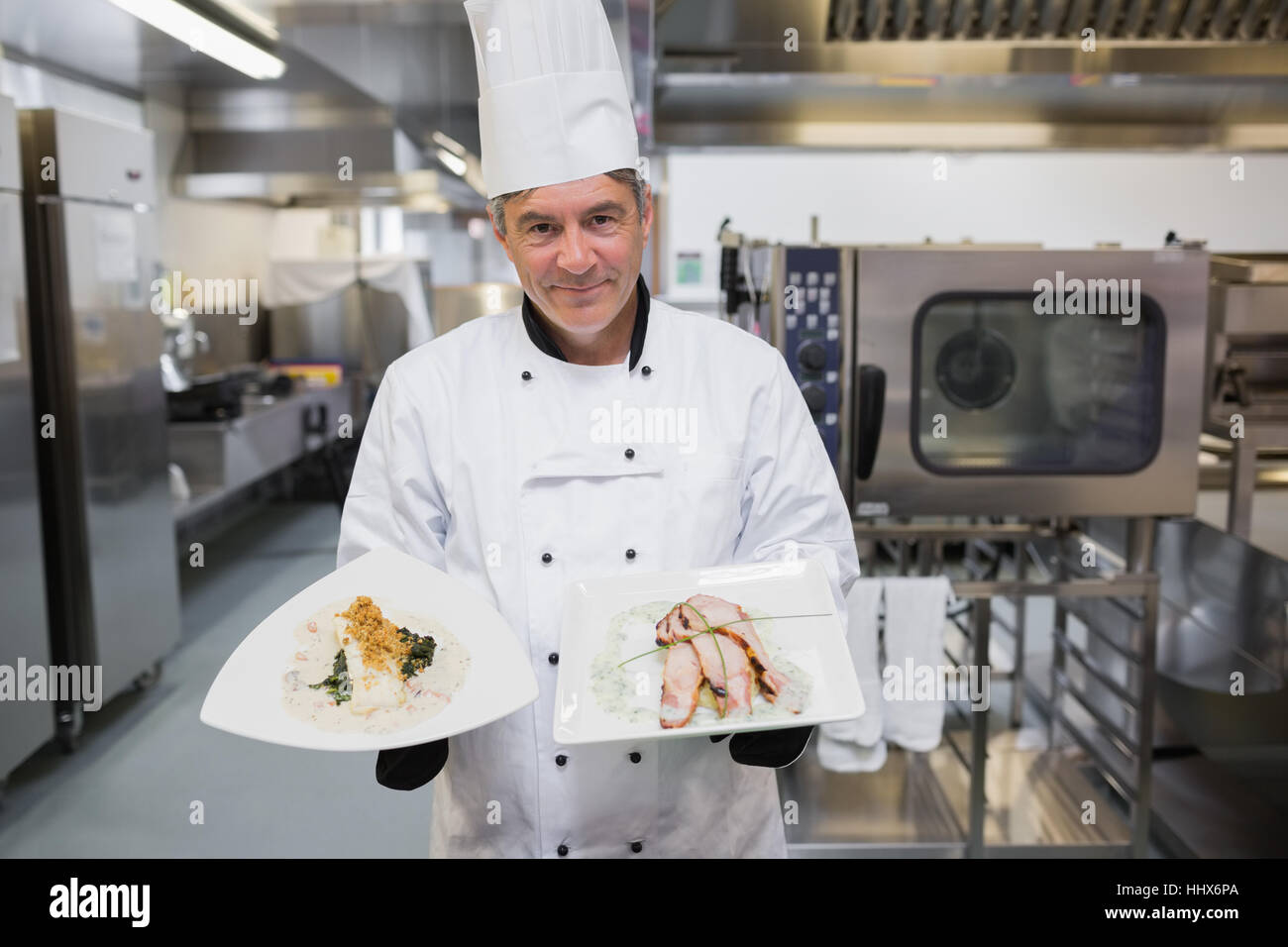 Smiling cook holding two chicken plates in the kitchen Stock Photo - Alamy