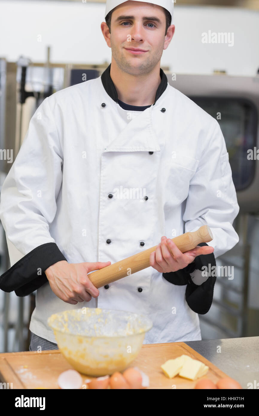 Baker holding a rolling pin while smiling in kitchen Stock Photo - Alamy