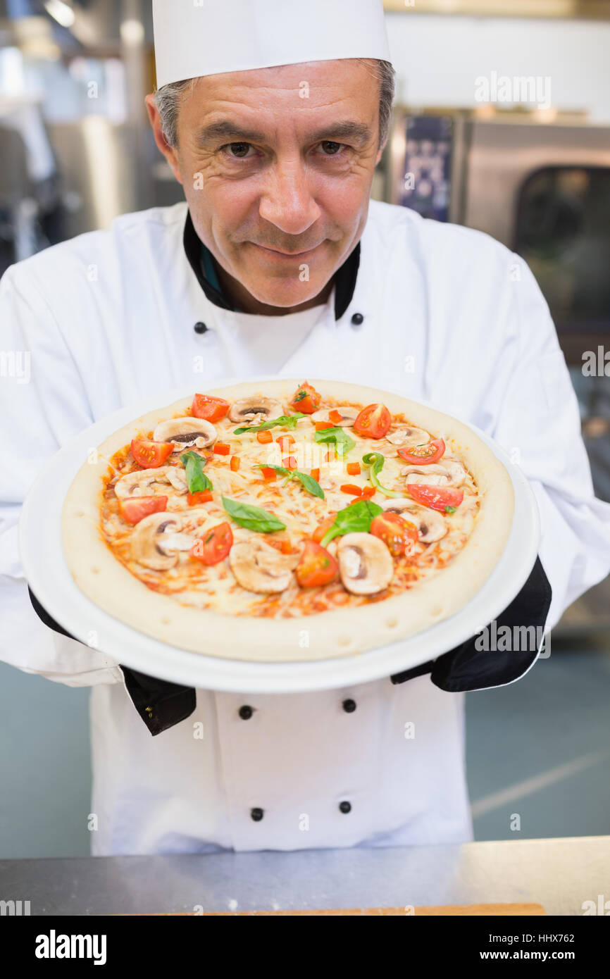 Man presenting a pizza in the kitchen Stock Photo - Alamy