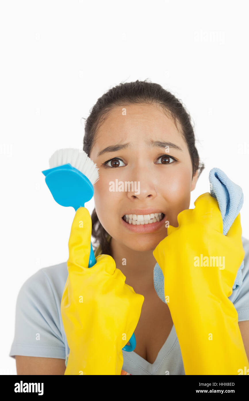 Stressed woman holding scrubbing brush and rag wearing rubber gloves ...