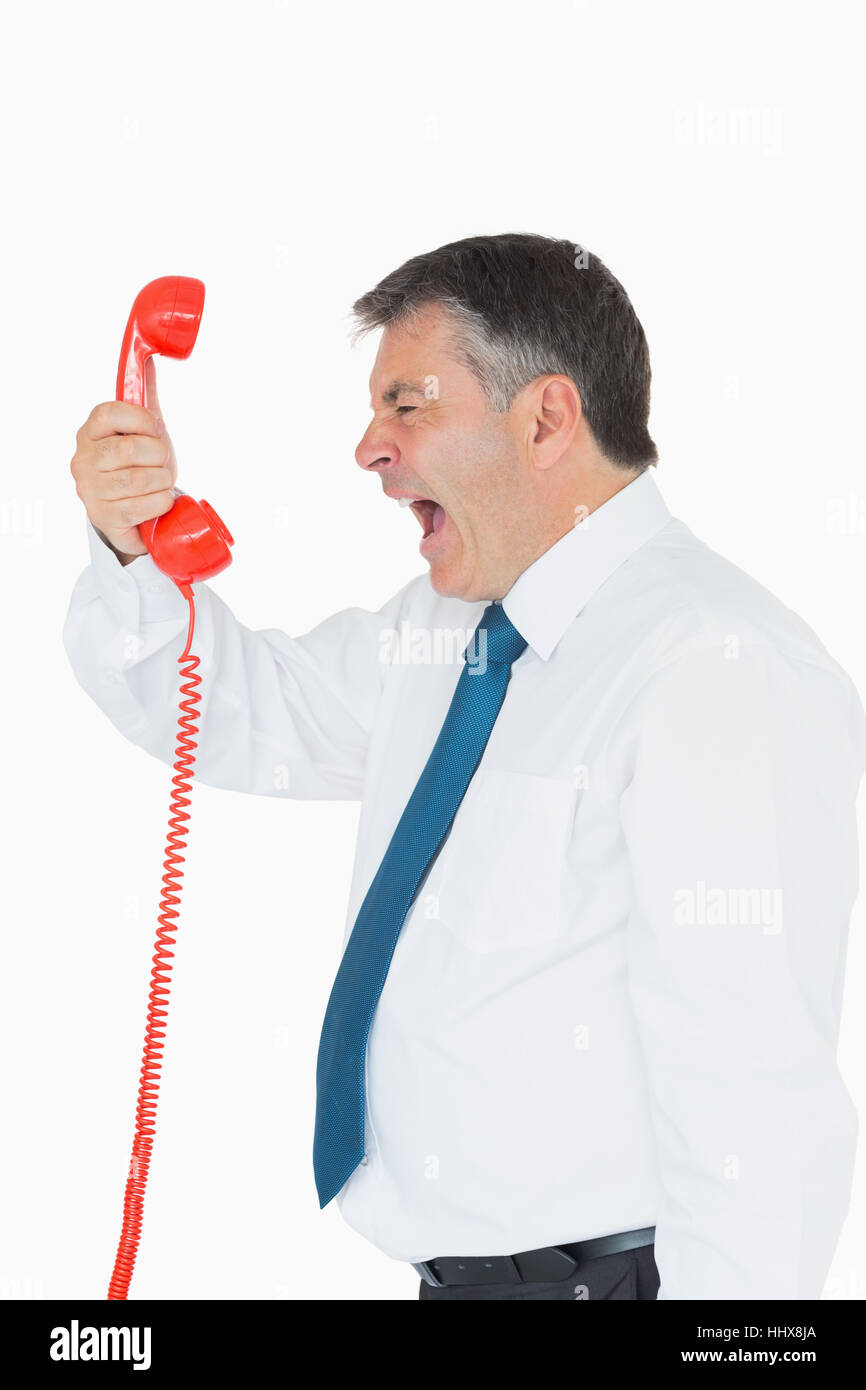 Businessman screaming directly into the red telephone handset Stock ...