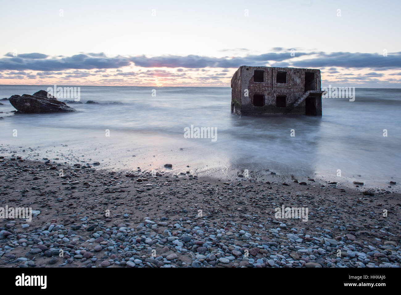 waves crushing over rocks and ruins of old fort at sunset on the beach ...