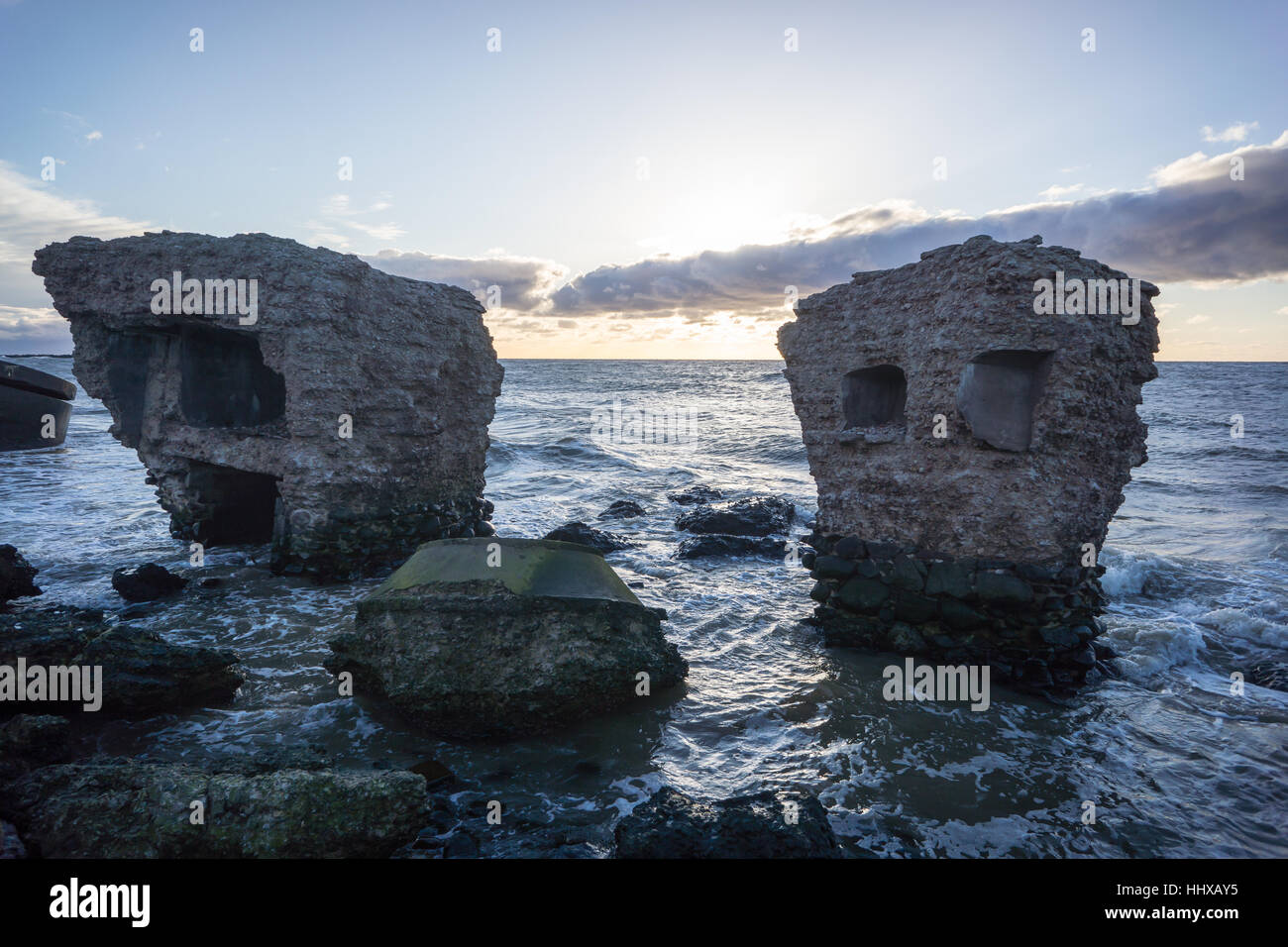 waves crushing over rocks and ruins of old fort at sunset on the beach ...