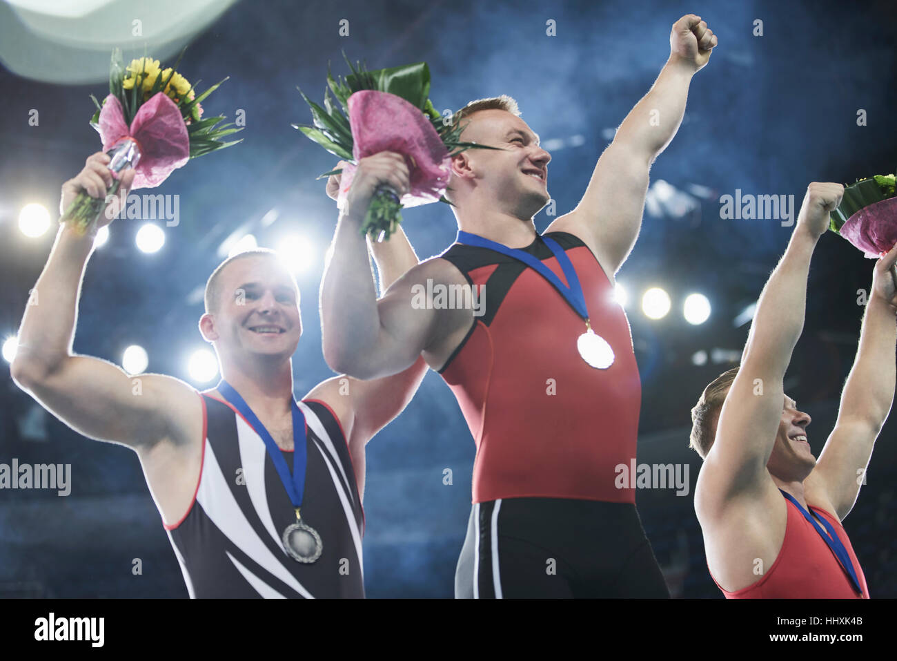 Enthusiastic gymnasts cheering celebrating victory on winners podium ...