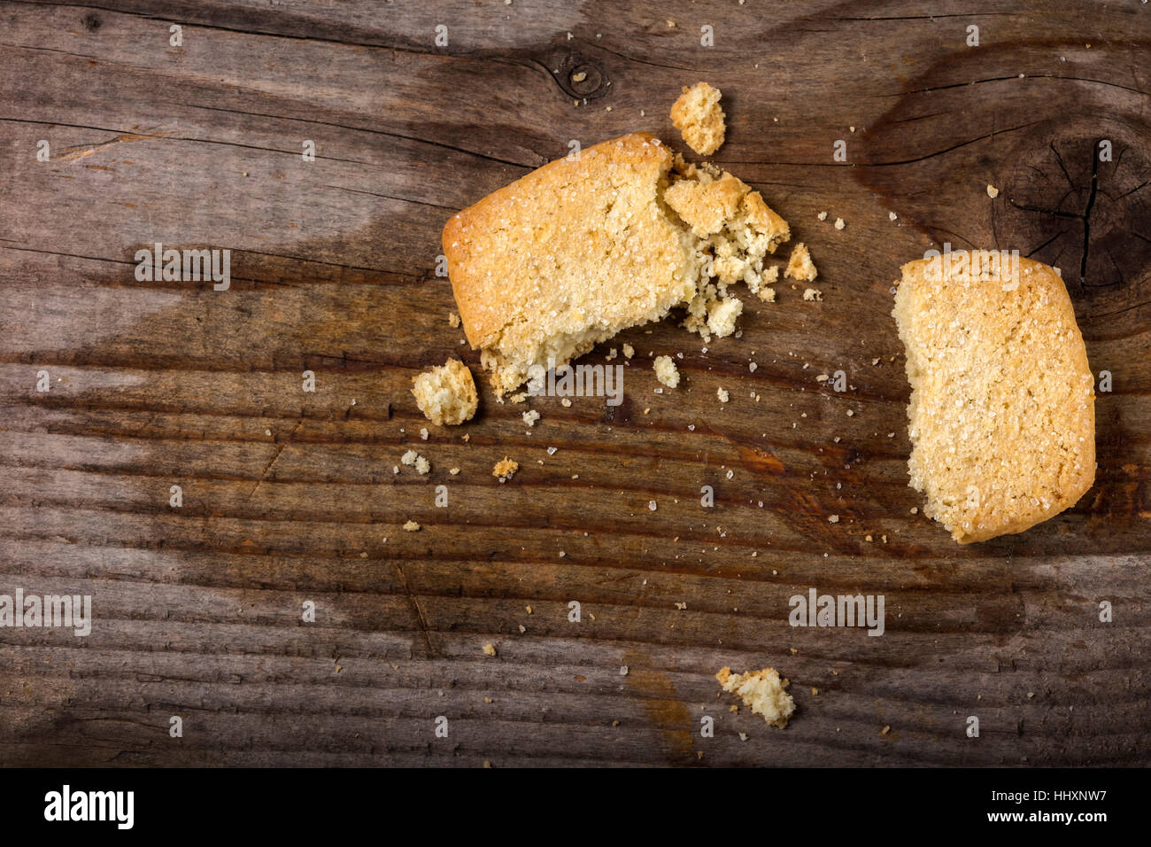 Broken butter cookies and crumbs over wooden background with copy space ...