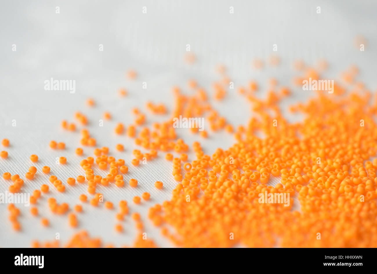 Seed beads of orange color on textile background Stock Photo - Alamy