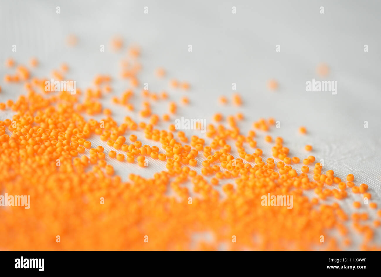 Seed beads of orange color on textile background Stock Photo - Alamy