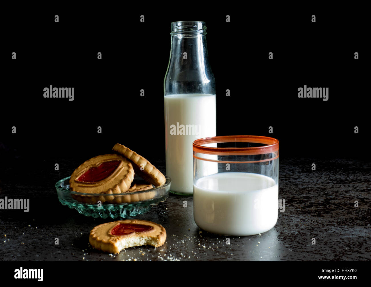 Glass and bottle of milk and biscuits on dark stone background Stock ...
