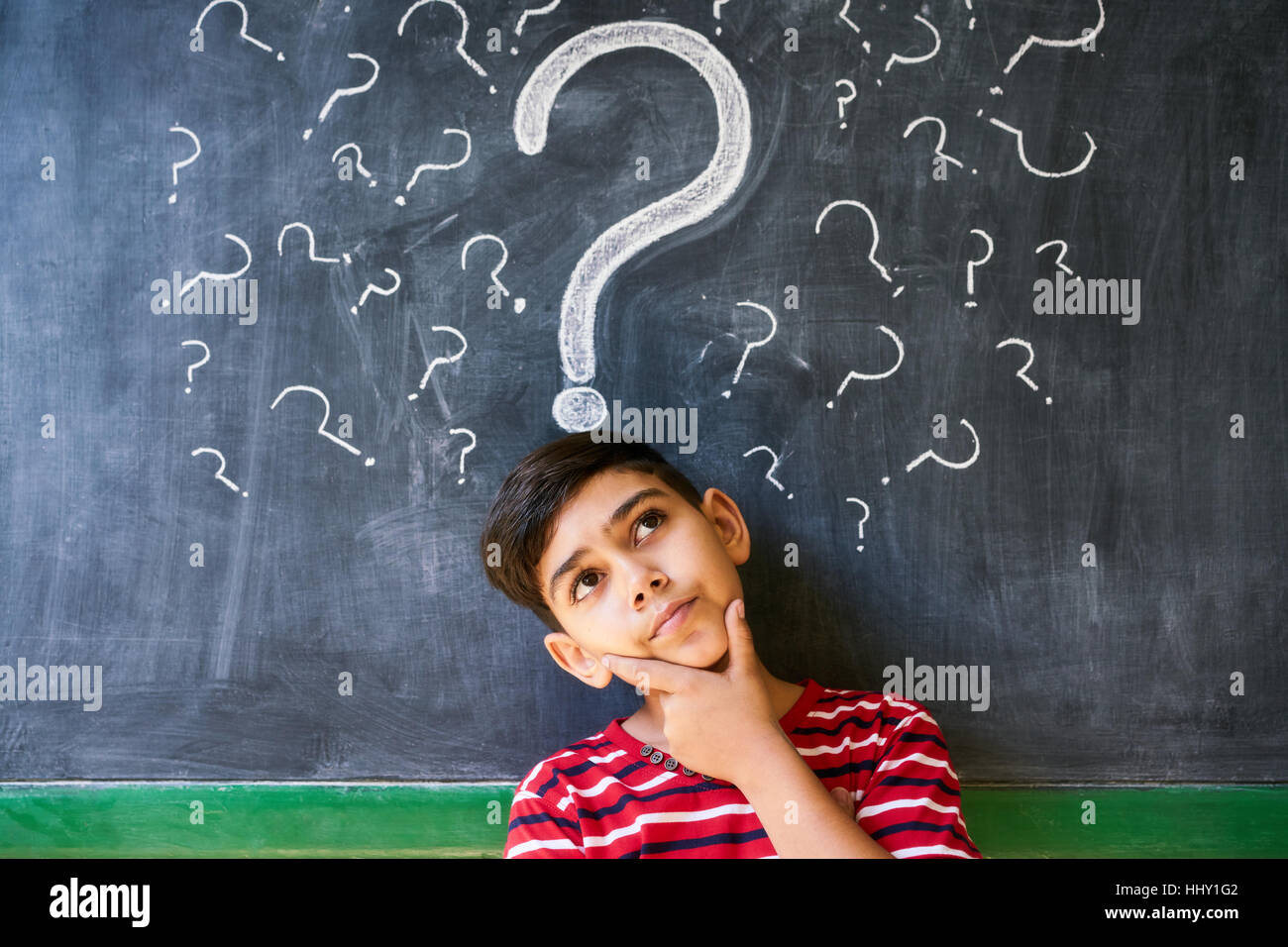 Concepts on blackboard at school. Hispanic boy with doubts and thoughts ...