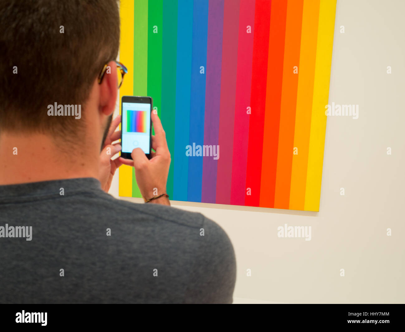 Man tacking a mobile phone picture of an art work with colourful ...