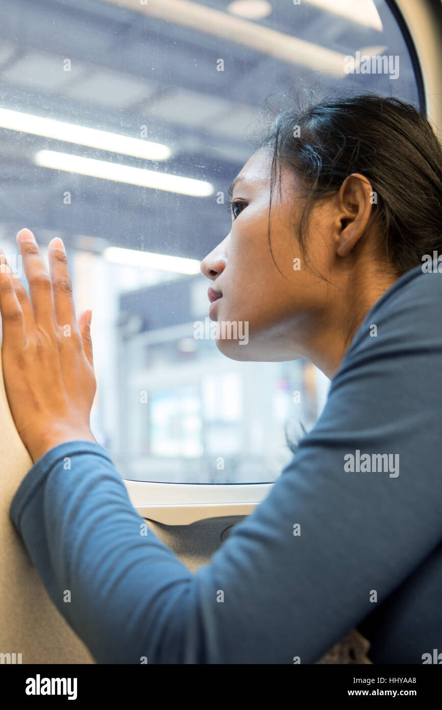 A woman looks out the window of the train on the railway station ...