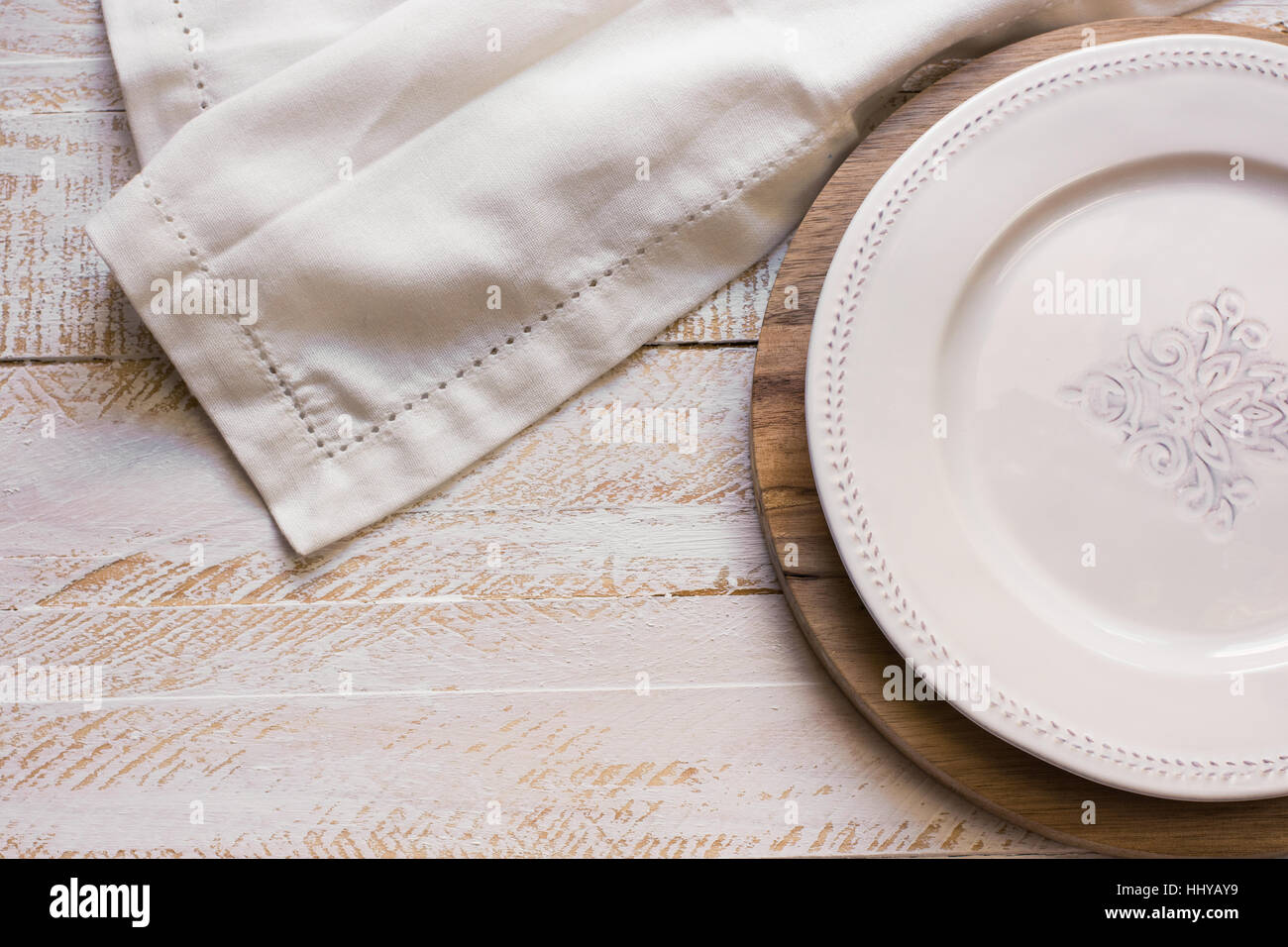 White vintage empty plate on round cutting board, linen cloth over ...