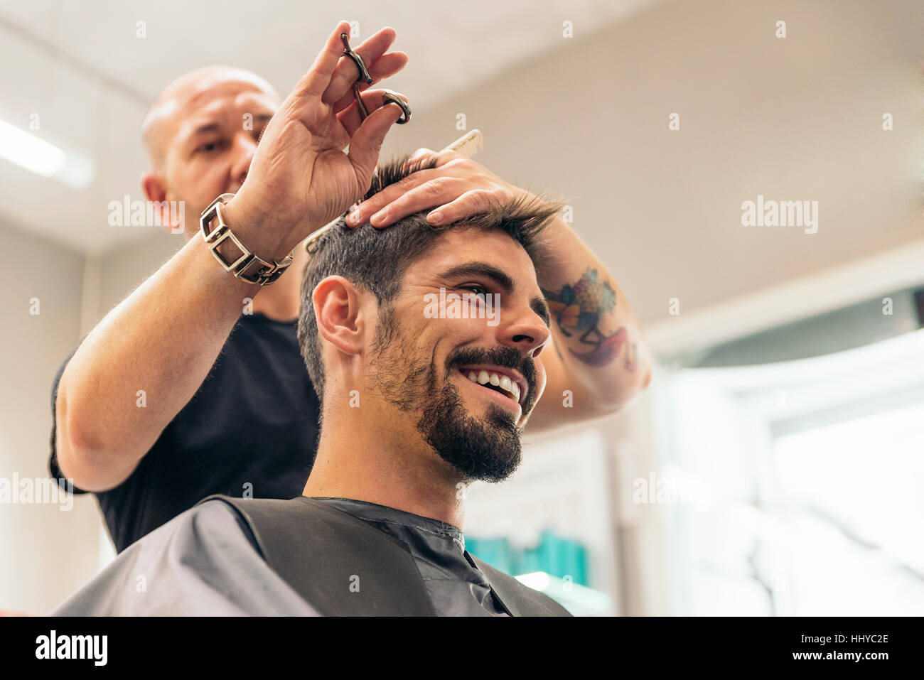Hairstylist making men's haircut to an attractive man in the beauty ...