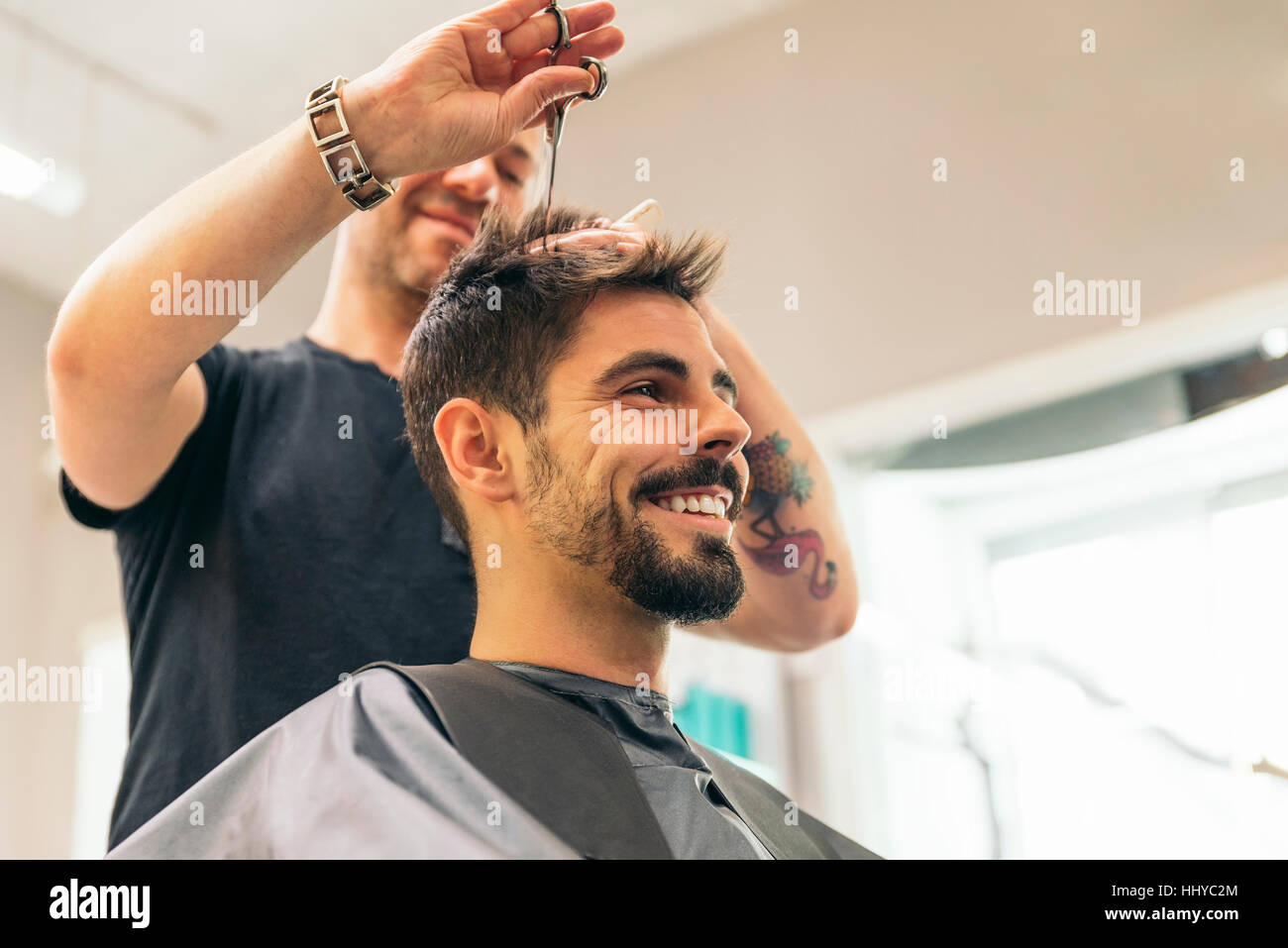 Hairstylist making men's haircut to an attractive man in the beauty ...