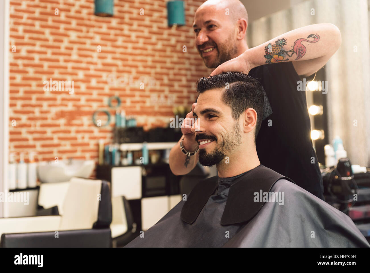 Hairstylist making men's haircut to an attractive man in the beauty ...