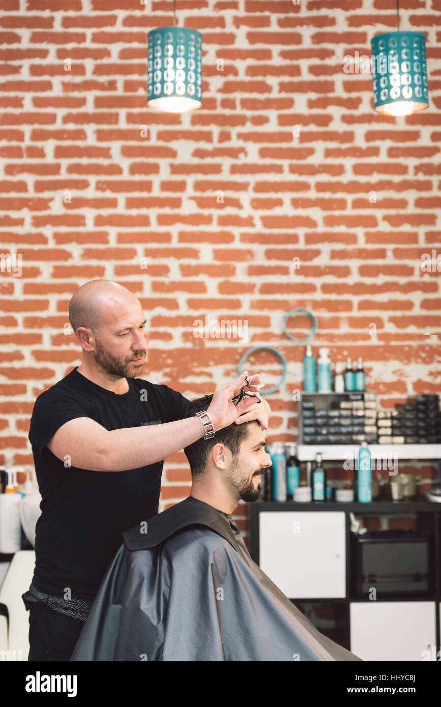 Hairstylist making men's haircut to an attractive man in the beauty ...