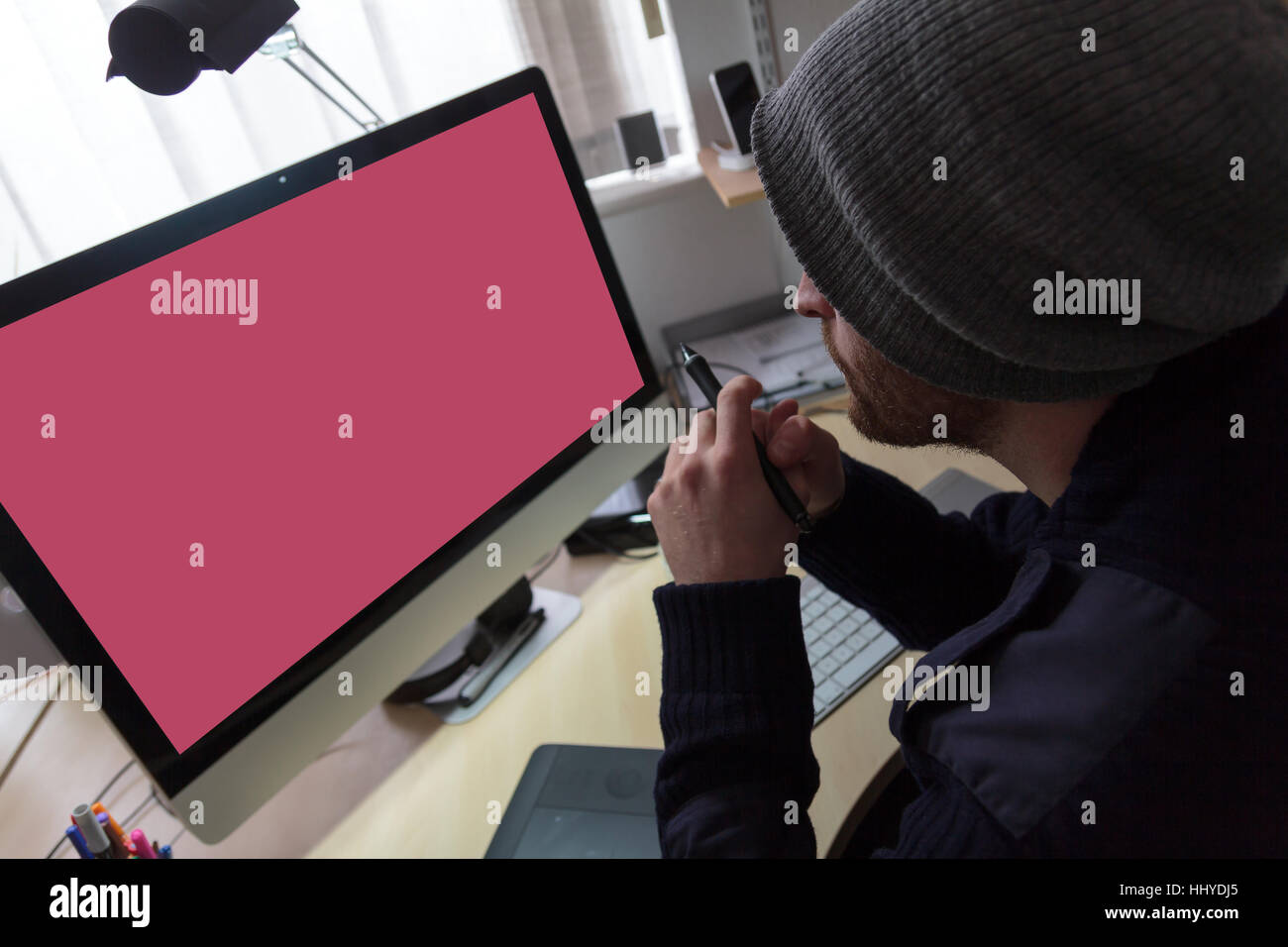 Web designer / developer sits at his desk holding his digital pen and ...