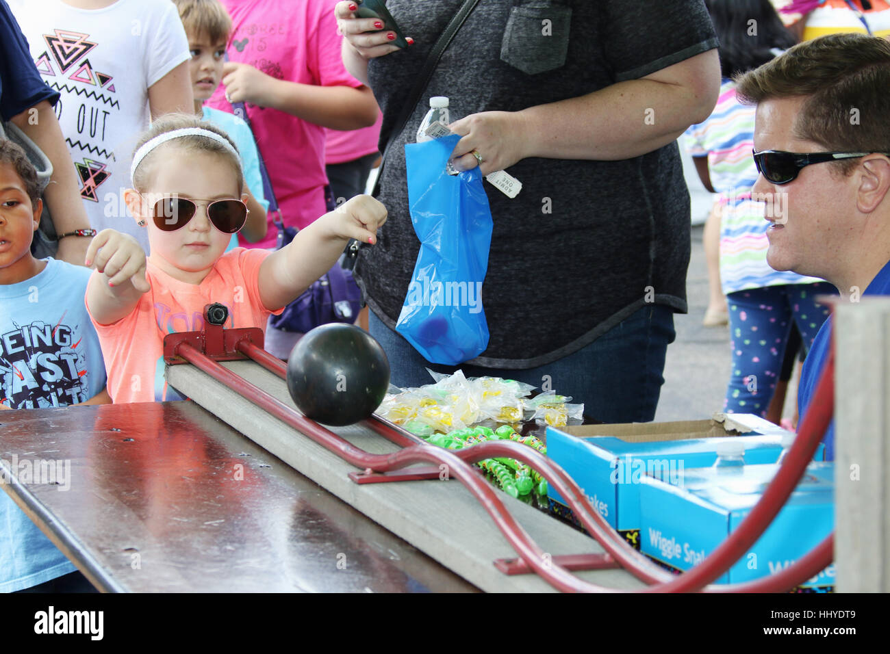 Young girl wearing sunglasses rolls a ball down a track in a Roller ...