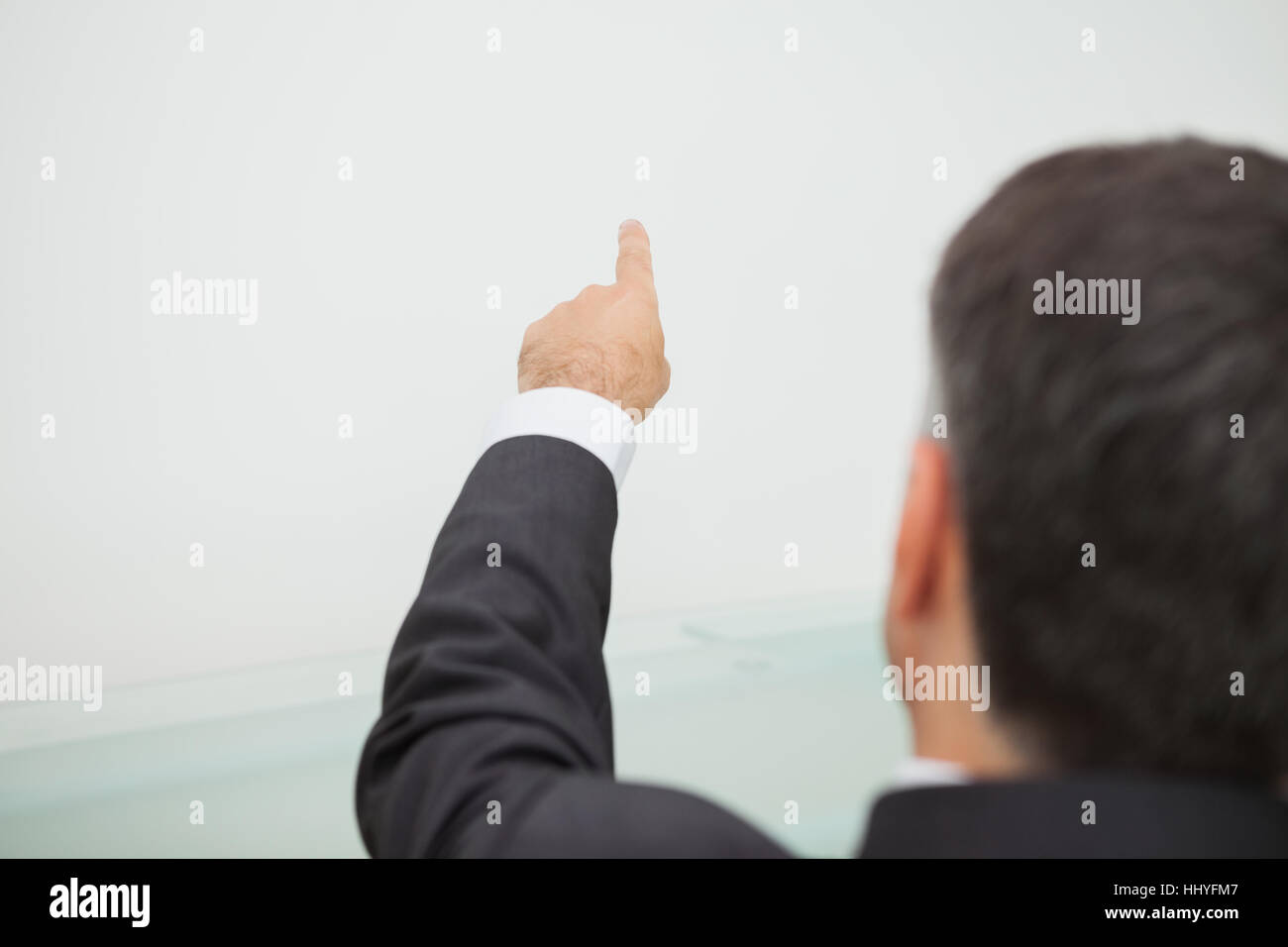 Businessman pointing to something on a white background Stock Photo - Alamy