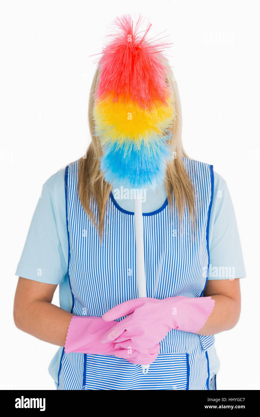 Cleaner holding a feather duster in front her face in the white ...