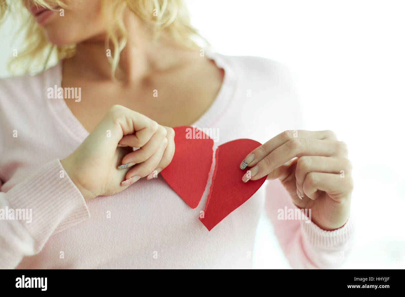 Pretty female showing red broken paper heart Stock Photo - Alamy