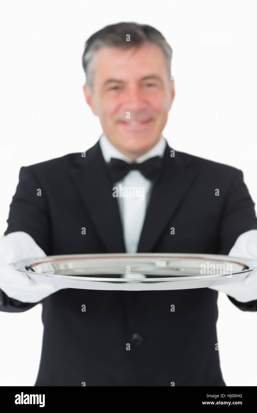 Waiter looking at the camera while holding a silver tray on white ...