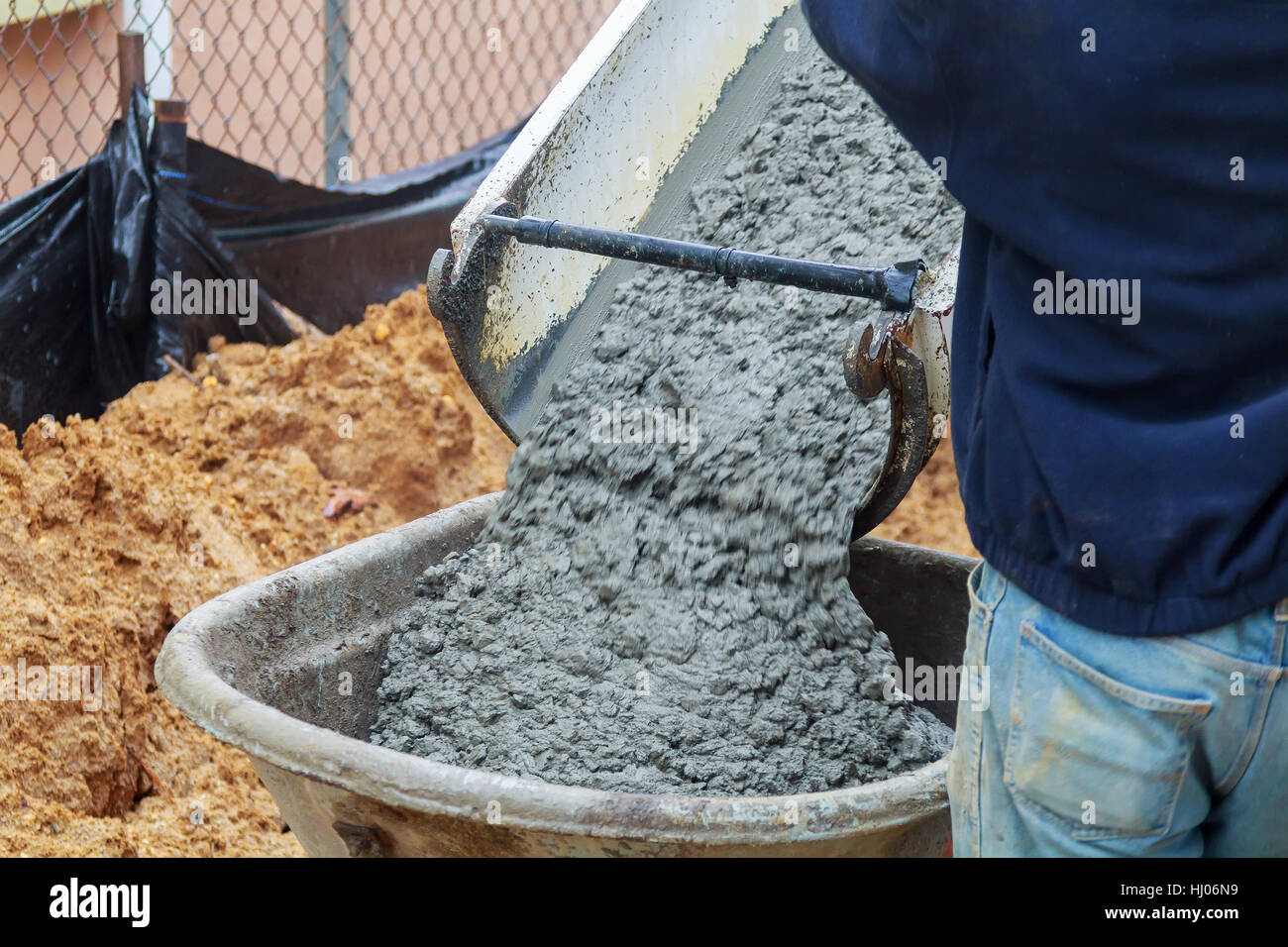 Concrete being poured from a truck into a concrete pump at a ...