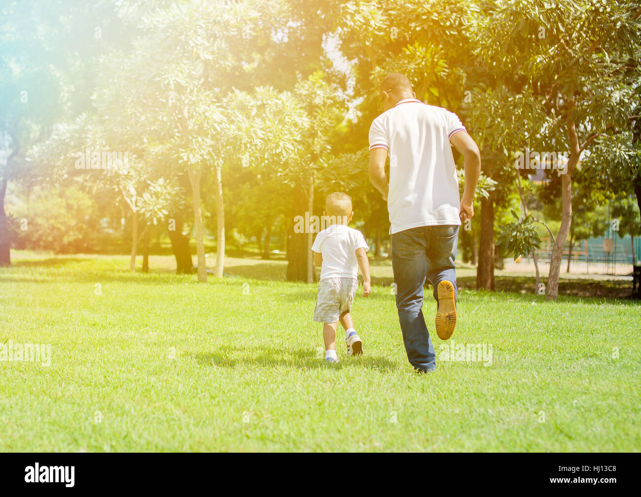 Father and son running and chasing each other in green park Stock Photo ...