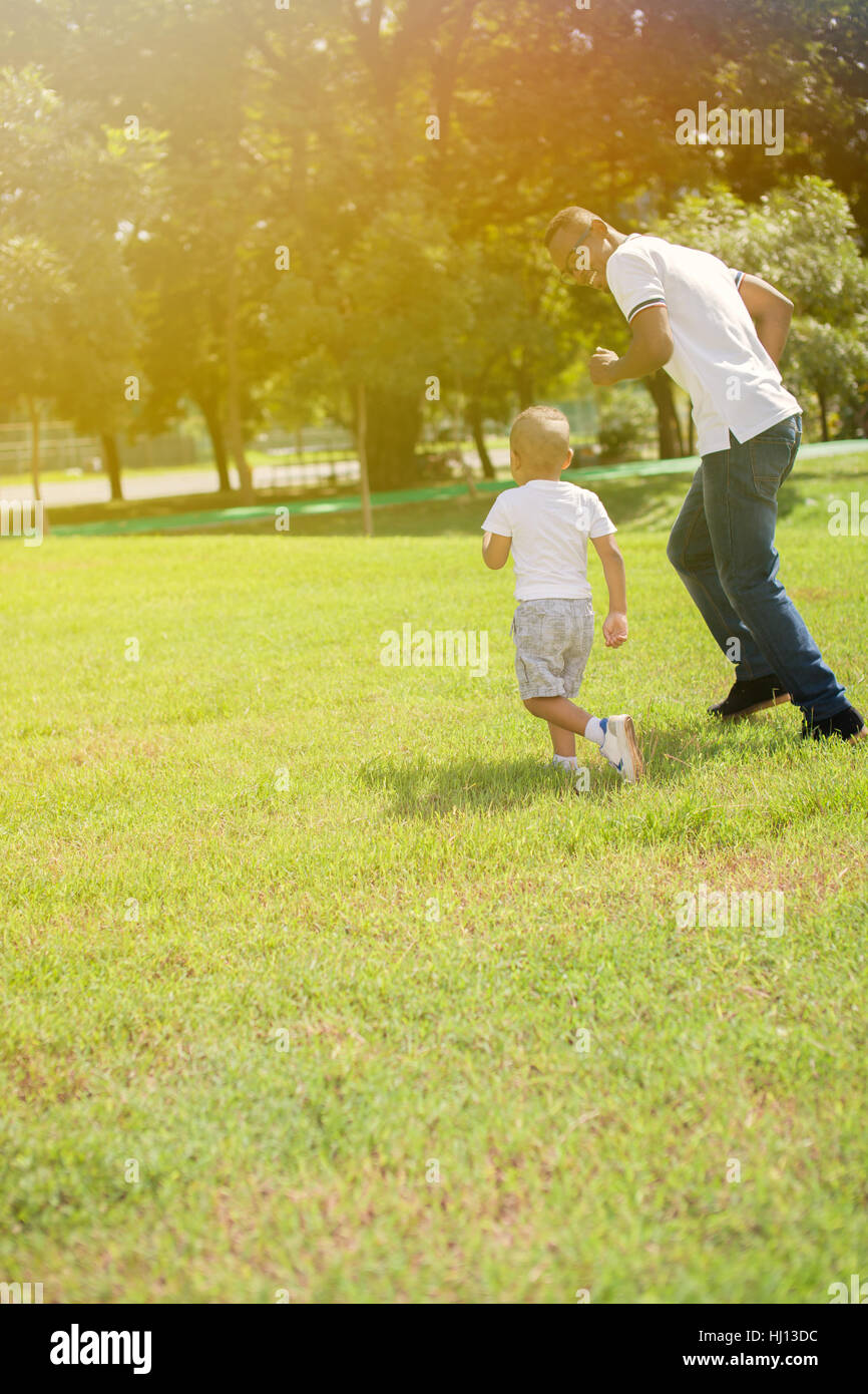 Father and son running and chasing each other in green park Stock Photo ...