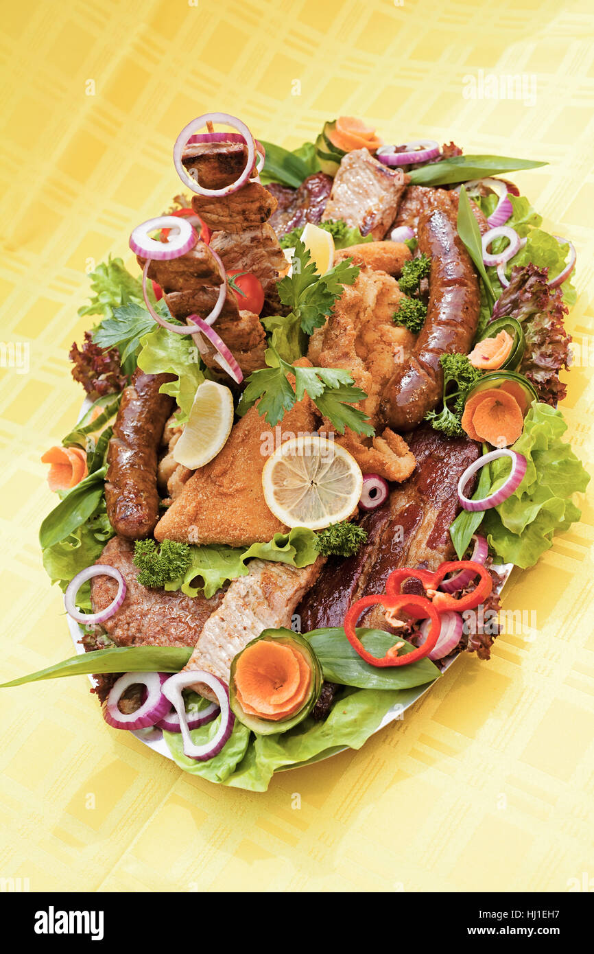 mixed meat decorated with lots of vegetables on oval on the yellow ...