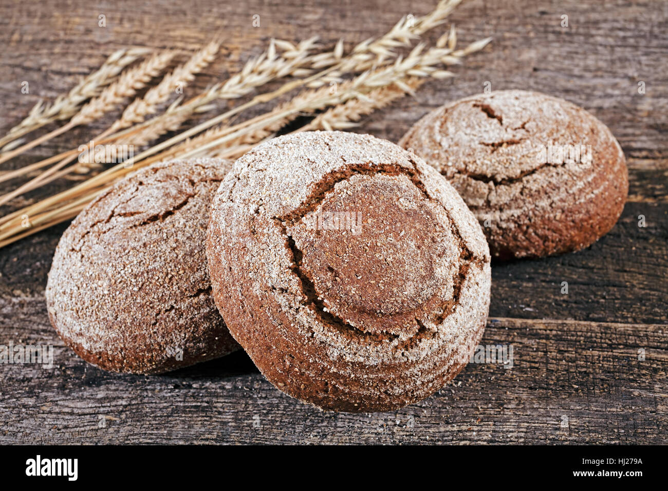 Decoration with a round rye bread and dried branches of rye on a wooden ...