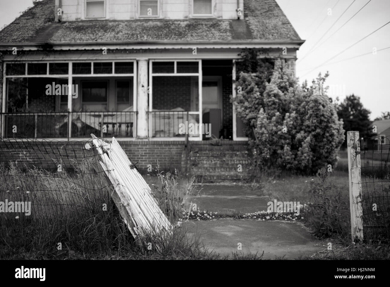 An abandoned house has a white wooden gate that has fallen down Stock ...
