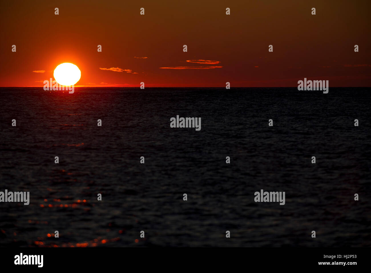 A red sun sits on the horizon of the Atlantic Ocean at first light ...