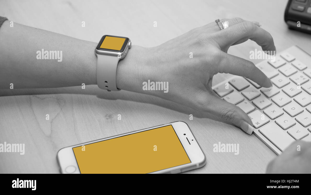 Support staff typing on keyboard. Shot also shows iWatch and iPhone ...