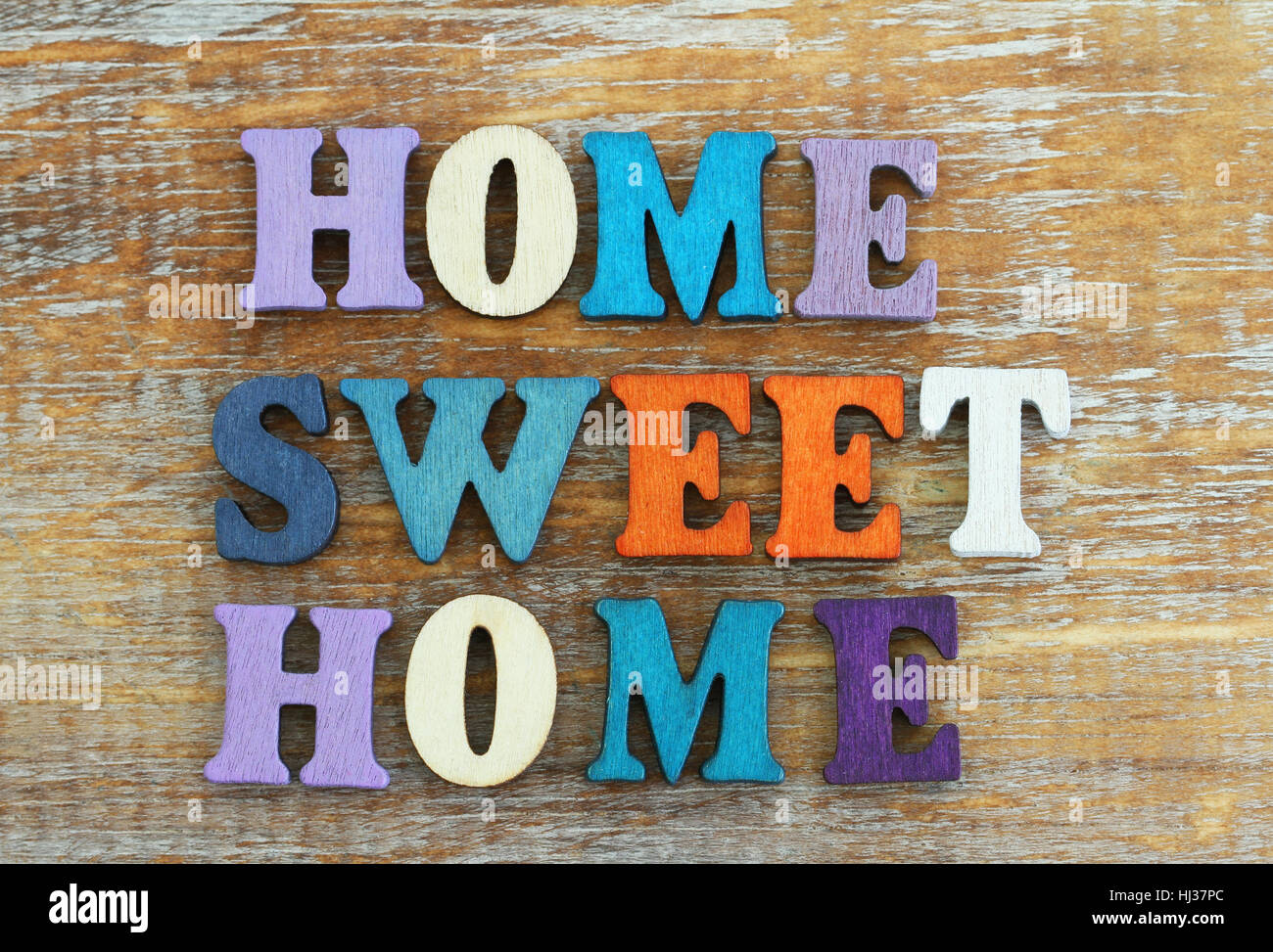 Home sweet home written with colorful letters on rustic wooden surface ...