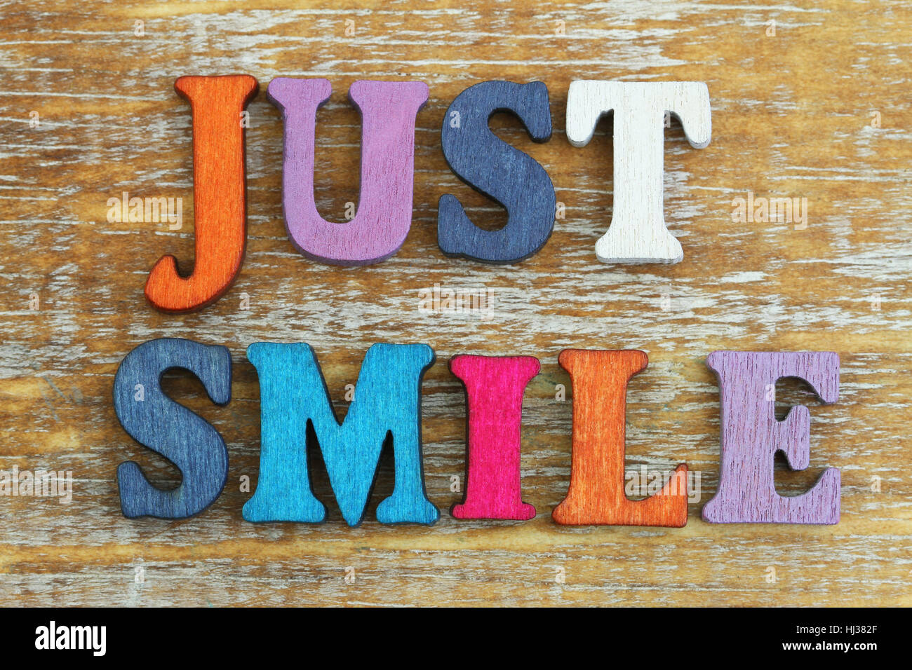 Just smile written with colorful letters on rustic wooden surface Stock ...