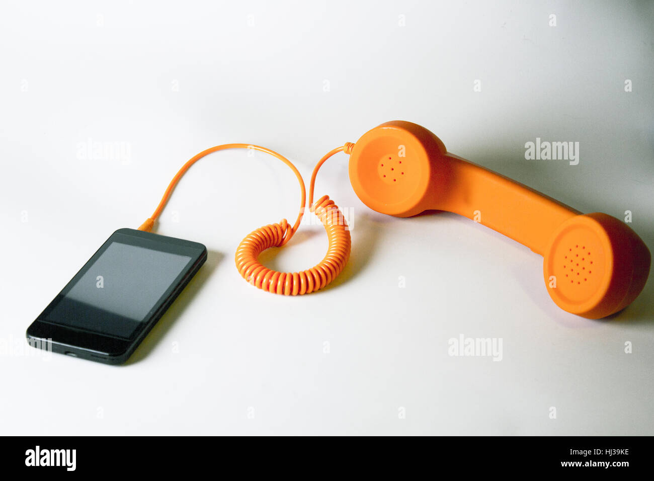 Orange analog phone and smartphone connected by a cable Stock Photo - Alamy