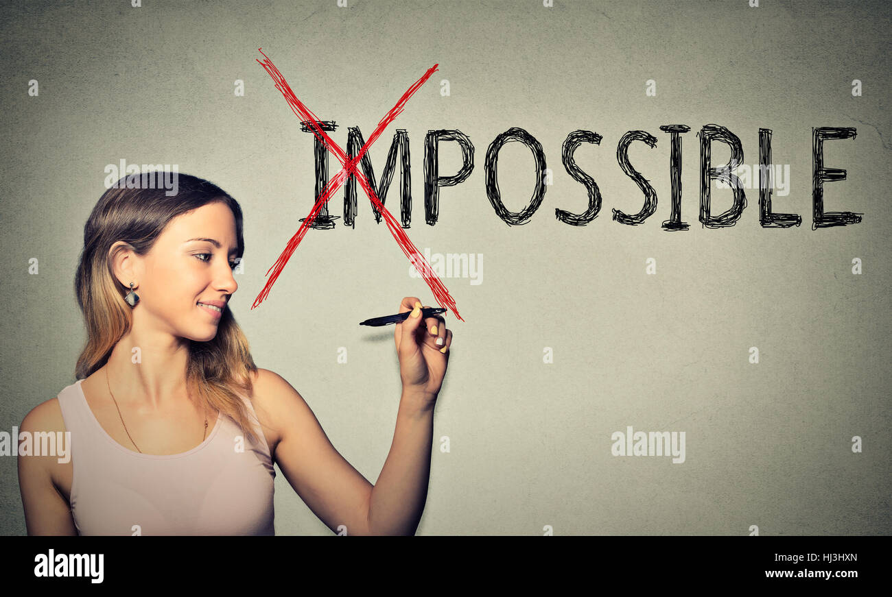 Young happy woman converting the word impossible to possible with pen ...