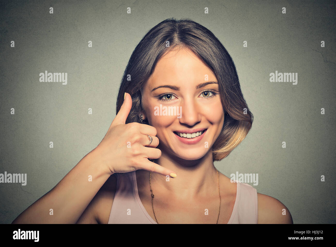 Portrait attractive young woman making showing call me sign and smiling ...